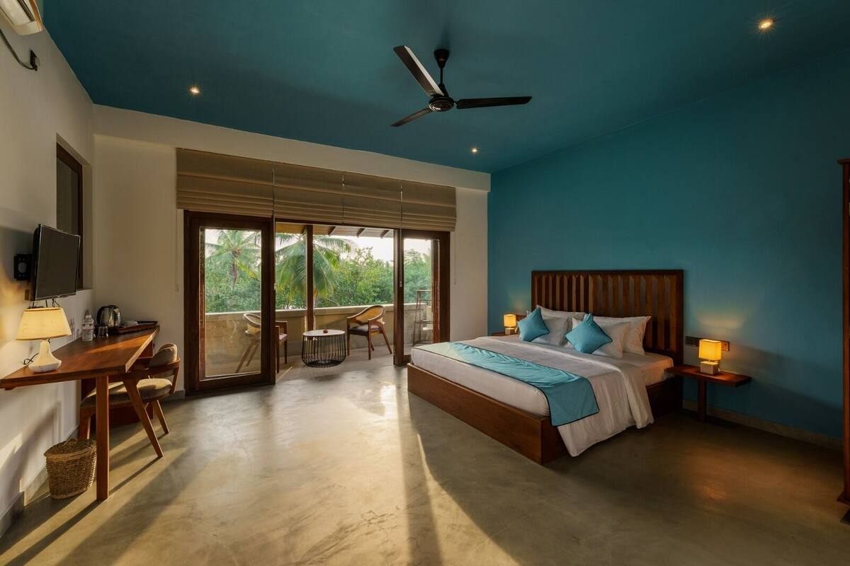 Quarto com cama, mesas de cabeceira, escrivaninha e televisão.