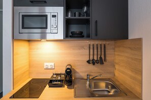 Uma cozinha compacta com micro-ondas embutido, cafeteira e pia.