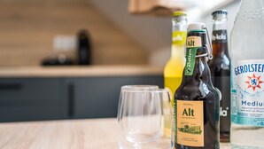 Uma garrafa de cerveja Bolten Alt, um copo e uma garrafa de água Gerolsteiner Medium sobre uma superfície de madeira.