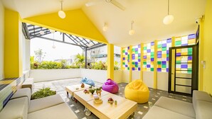 Quarto claro e moderno com uma mesa de madeira, poltronas de feltro e uma parede colorida.