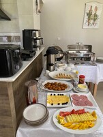 Um buffet de café da manhã com diversos alimentos e eletrodomésticos.