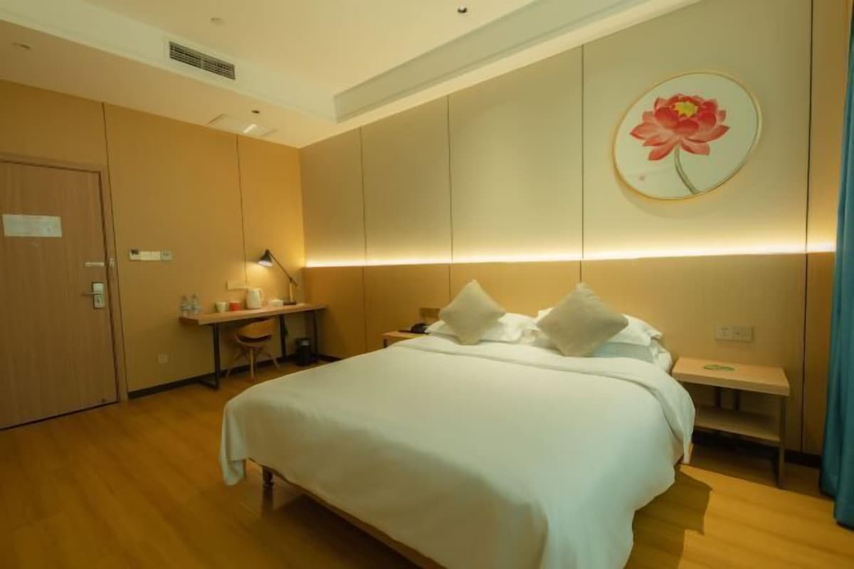 Quarto de hotel com cama, mesa de cabeceira e escrivaninha com abajur.