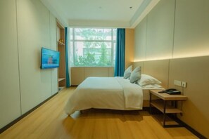 Quarto de hotel com cama, mesa de cabeceira com telefone, televisão na parede e janela com cortinas.