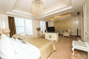 Quarto de hotel com uma cama grande, televisão, escrivaninha e uma cadeira.