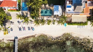 Vista aérea de um resort com praia, piscina e vários edifícios.
