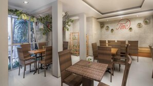 Uma sala de jantar moderna com móveis de vime, uma parede de tijolos e um letreiro com a palavra 'Time'.
