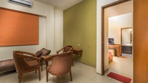 Uma sala de estar moderna com um sofá, duas poltronas, uma mesinha e um ar condicionado fixado na parede.
