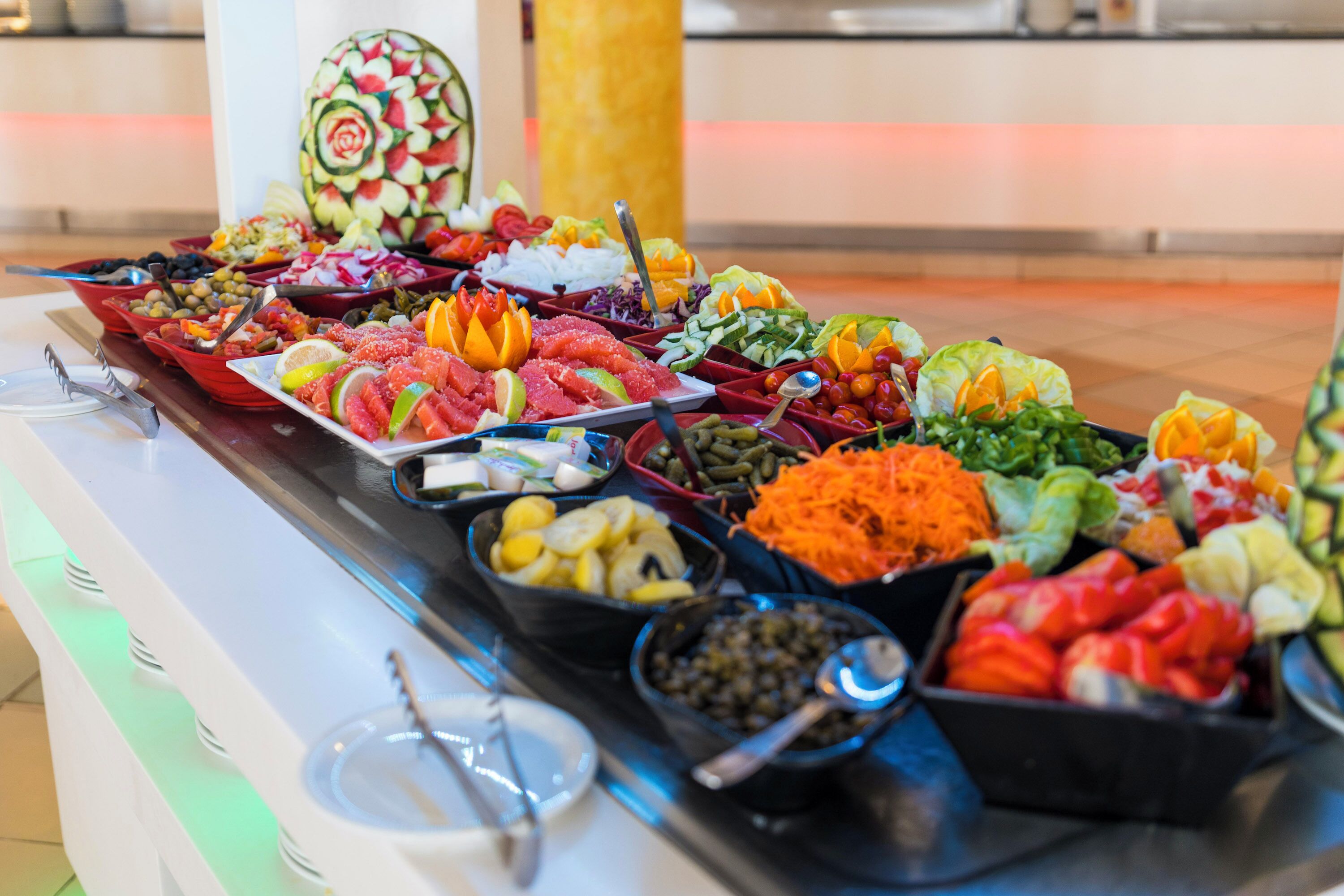 Buffet com diversas opções de alimentos, incluindo frutas, legumes e saladas.