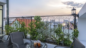 Varanda com móveis de vime, piso de azulejos e vista para a paisagem urbana.