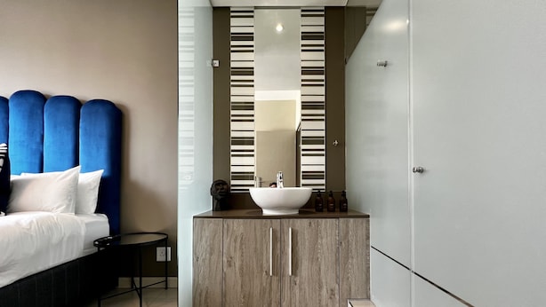 Quarto moderno com cama grande, mesa de cabeceira, toucador embutido com espelho e guarda-roupa.