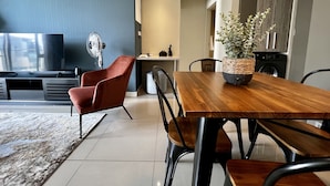 Uma sala de estar moderna com uma mesa de jantar de madeira, uma poltrona vermelha e uma grande televisão de tela plana.