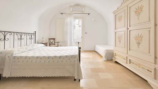 Um quarto com uma cama, um guarda-roupa e um banquinho.