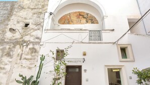 Um edifício com fachada branca, porta de madeira e uma pequena janela.