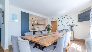 Uma sala de jantar moderna com mesa de madeira e cadeiras estofadas cinzentas.