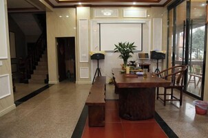 Uma sala de jantar ampla com uma longa mesa de madeira, cadeiras e um banco. Há uma planta na mesa e uma grande janela com vista.