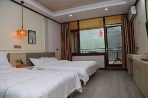 Quarto de hotel com duas camas, teto de madeira, janela grande com cortinas e varanda.
