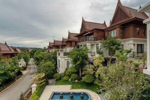 Resort com várias villas, piscina e vegetação exuberante.