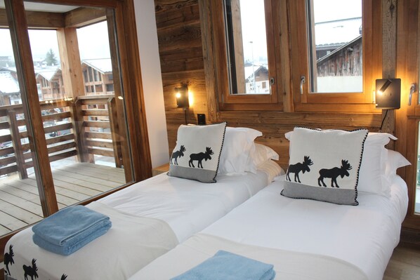 Quarto de cabana de madeira com duas camas, cada uma com travesseiro branco com silhueta de burro.