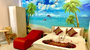Quarto com cama, uma cadeira vermelha, guarda-roupa de madeira e um mural na parede com uma cena de praia.