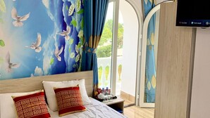 Quarto de hotel com cama, televisão e janela com cortinas.