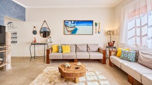 Uma sala de estar com sofá, mesa de centro e obras de arte na parede.
