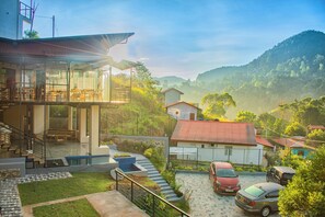 Um edifício moderno com fachada de vidro, área de estar ao ar livre e vista para uma paisagem montanhosa.