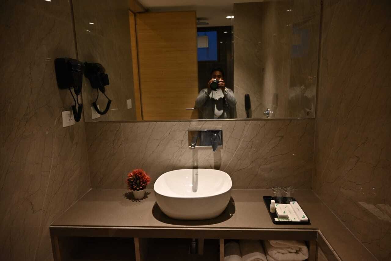 Um banheiro moderno com um espelho grande, um lavatório redondo e um porta-toalhas.