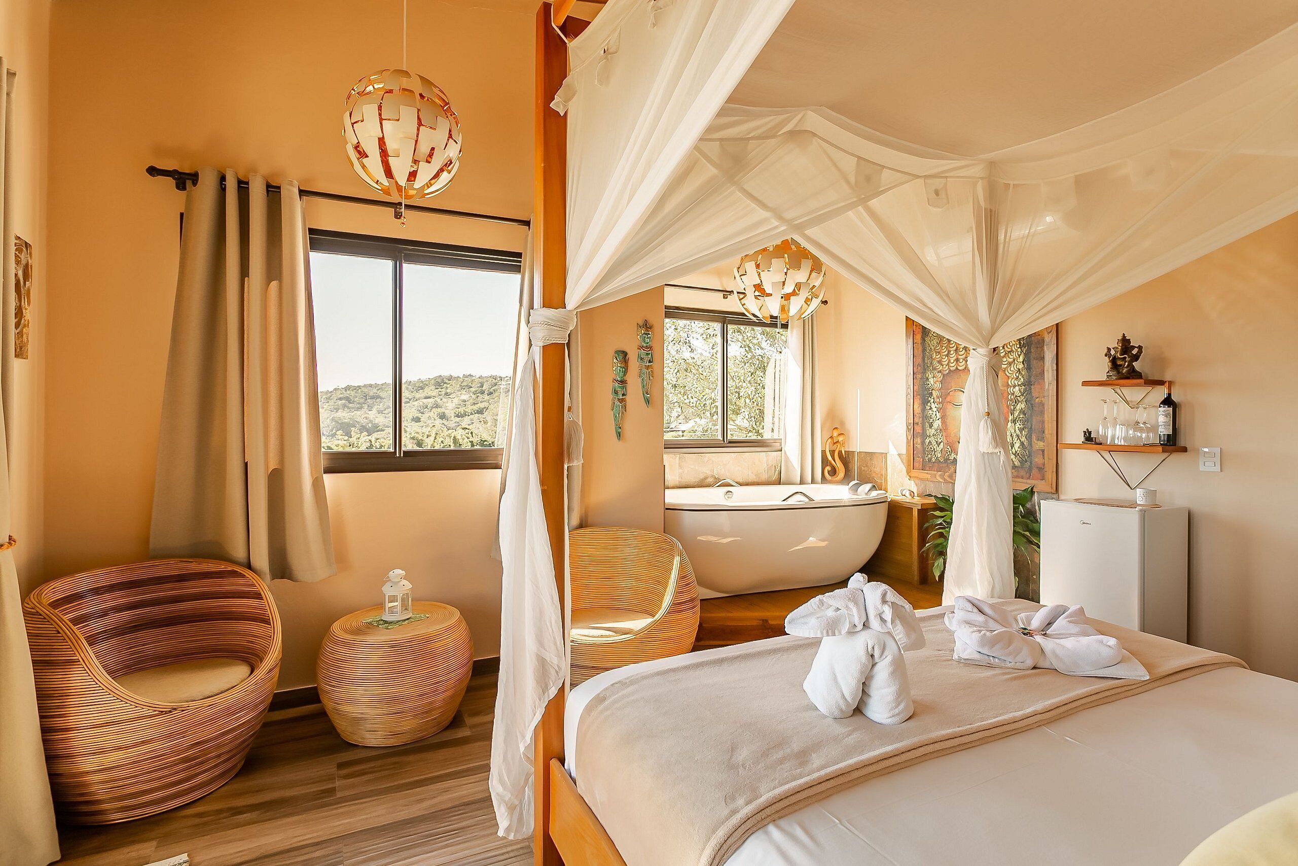 Quarto com cama de dossel, banheira e uma grande janela com vista para as colinas.