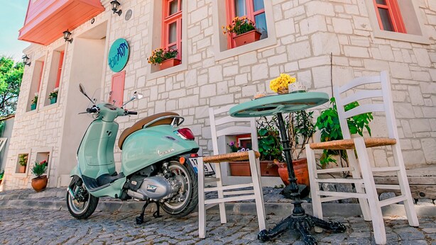 Um edifício rosa e branco com uma scooter estacionada na frente.