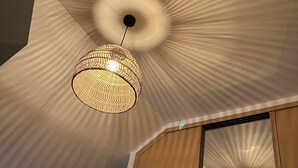 Um interior moderno com design de teto único, uma luminária pendente de vime e um espelho grande que reflete o ambiente.