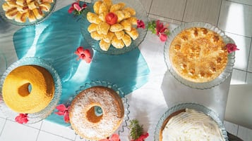 Uma mesa com diversos doces, incluindo bolos e pastéis, disposta sobre uma toalha azul.
