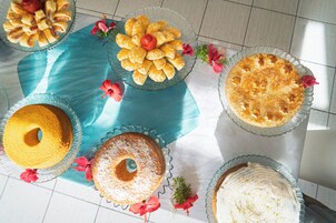 Uma mesa com diversos doces, incluindo bolos e pastéis, disposta sobre uma toalha azul.