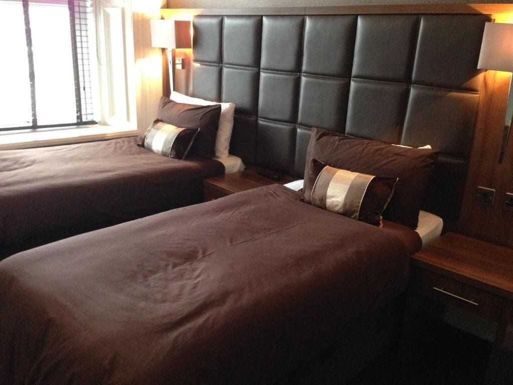 Quarto de hotel com duas camas, cada uma com cabeceira e mesas de cabeceira.