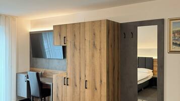 Quarto de hotel moderno com guarda-roupa de madeira, escrivaninha, cadeira e cama.