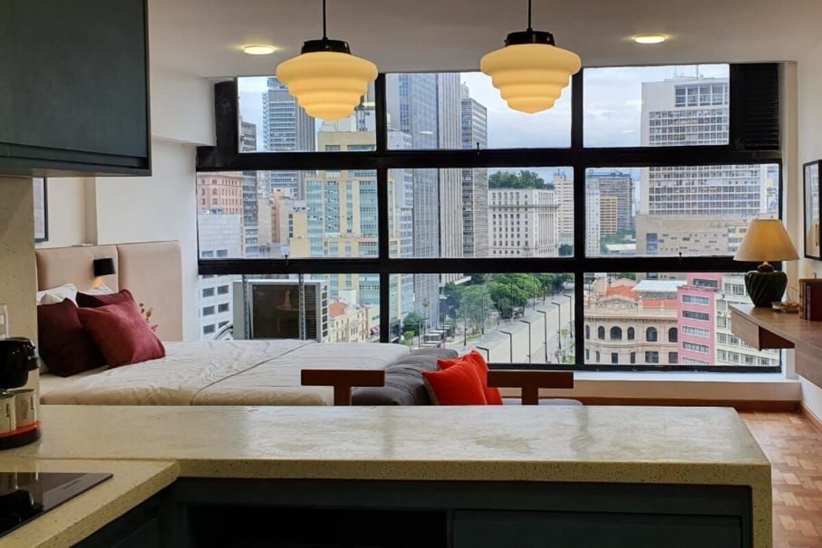 Cozinha moderna com uma janela grande, espaço de refeições e uma cama.