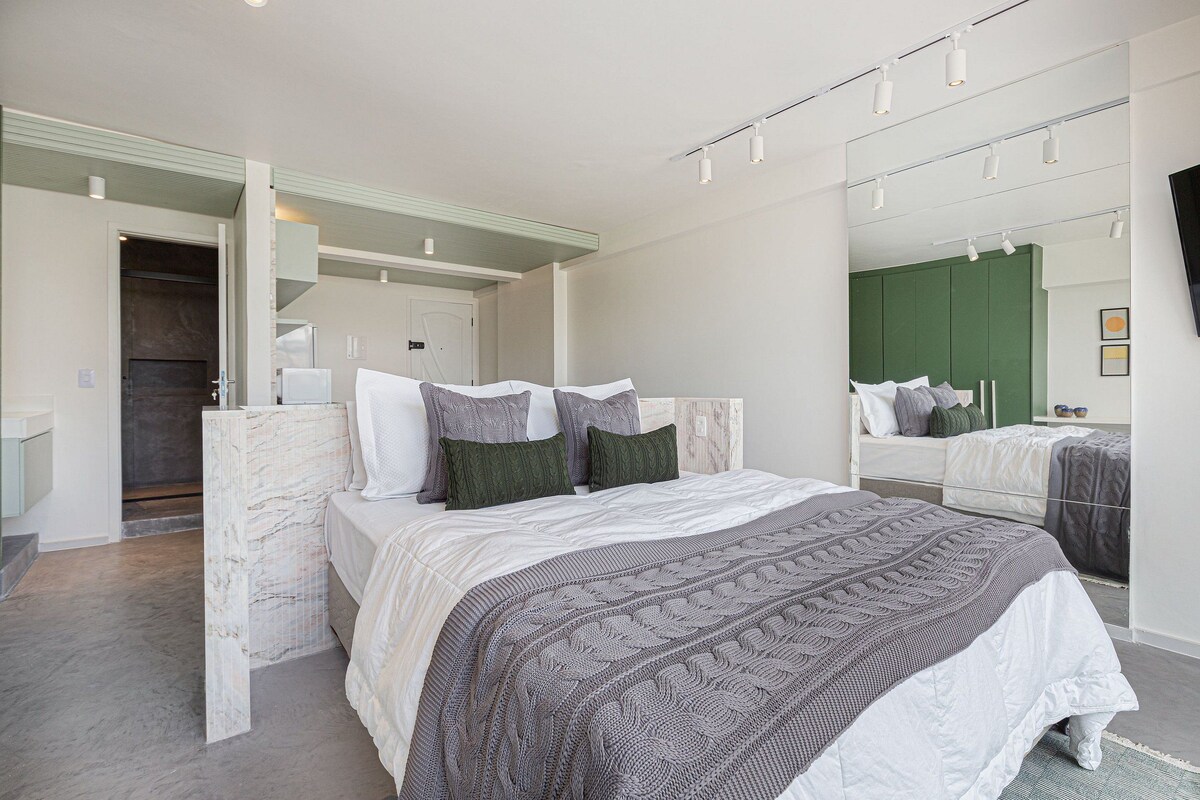 Quarto com uma cama grande, um espelho e um guarda-roupa verde.
