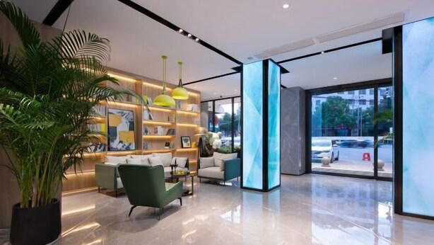 Um lobby moderno com uma receção, área de estar e uma grande janela com vista para a rua.