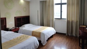 Quarto de hotel com duas camas, chão de madeira, janela com cortinas e parede com desenhos circulares.