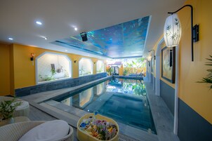 Piscina com afrescos no teto, área de estar com assentos e vista para o exterior.