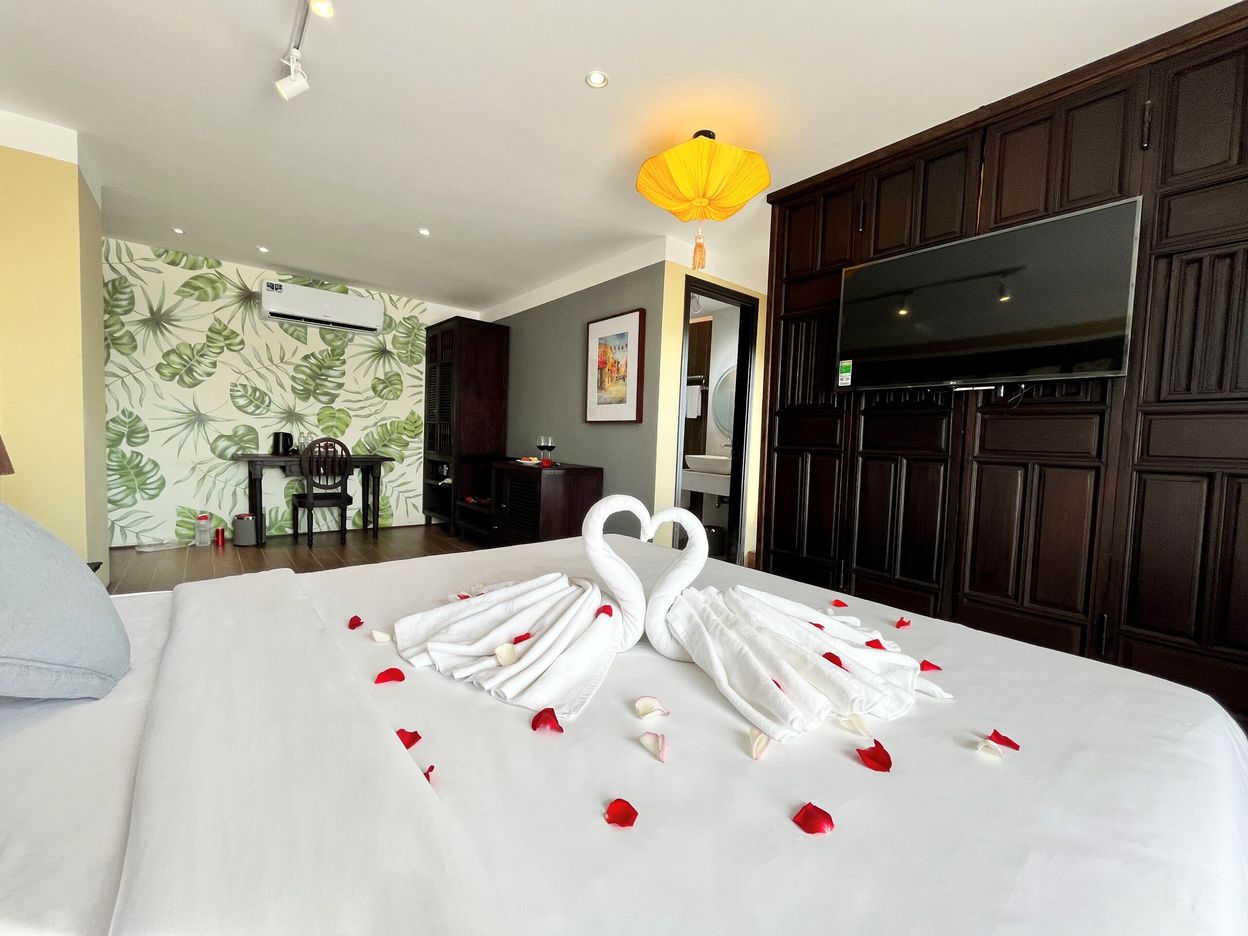 Quarto de hotel com cama, televisão, escrivaninha e cadeira.