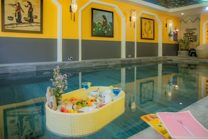Área da piscina com espaço de refeições, incluindo uma cesta de comida e bebidas, cercada por obras de arte nas paredes.