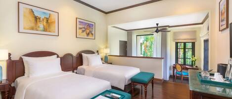 Quarto de hotel com duas camas, uma escrivaninha e vista para o exterior.