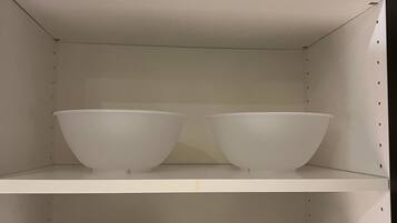 Cozinha com armários brancos e duas tigelas brancas na prateleira inferior.