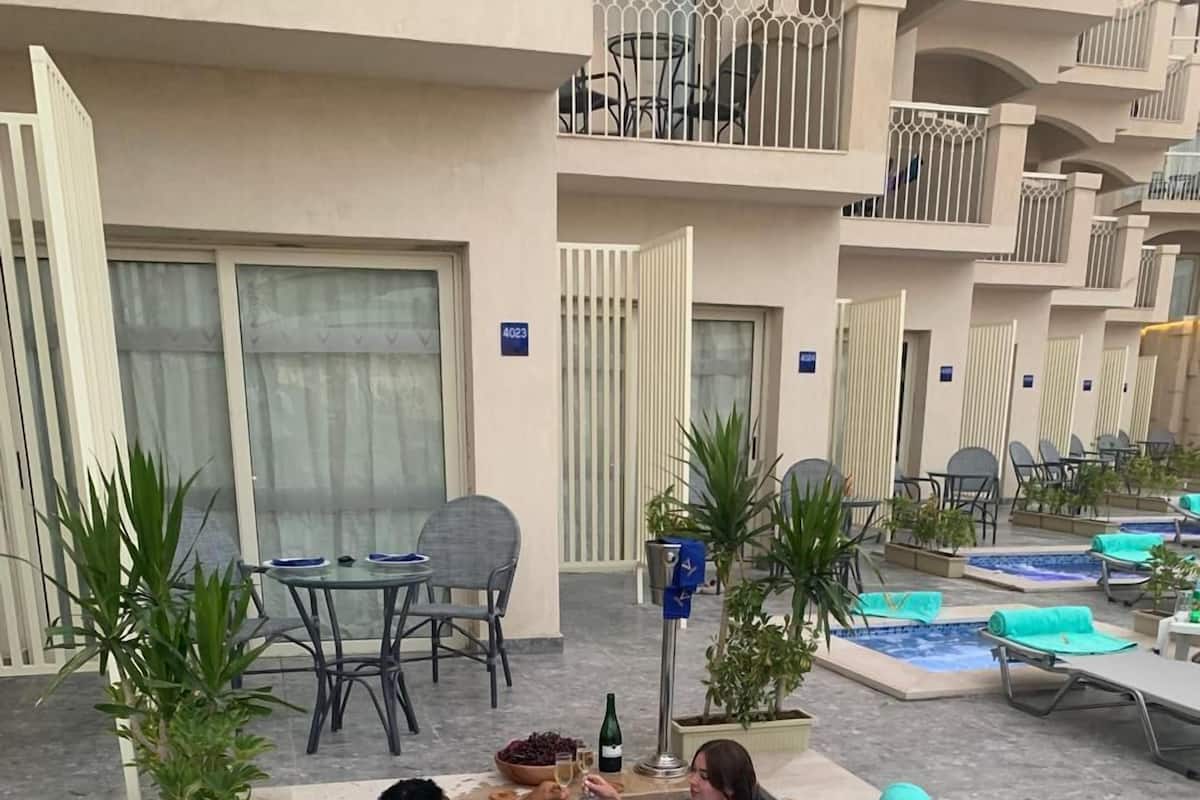 Uma área de piscina no terraço com duas banheiras de hidromassagem, espreguiçadeiras e plantas em vasos.