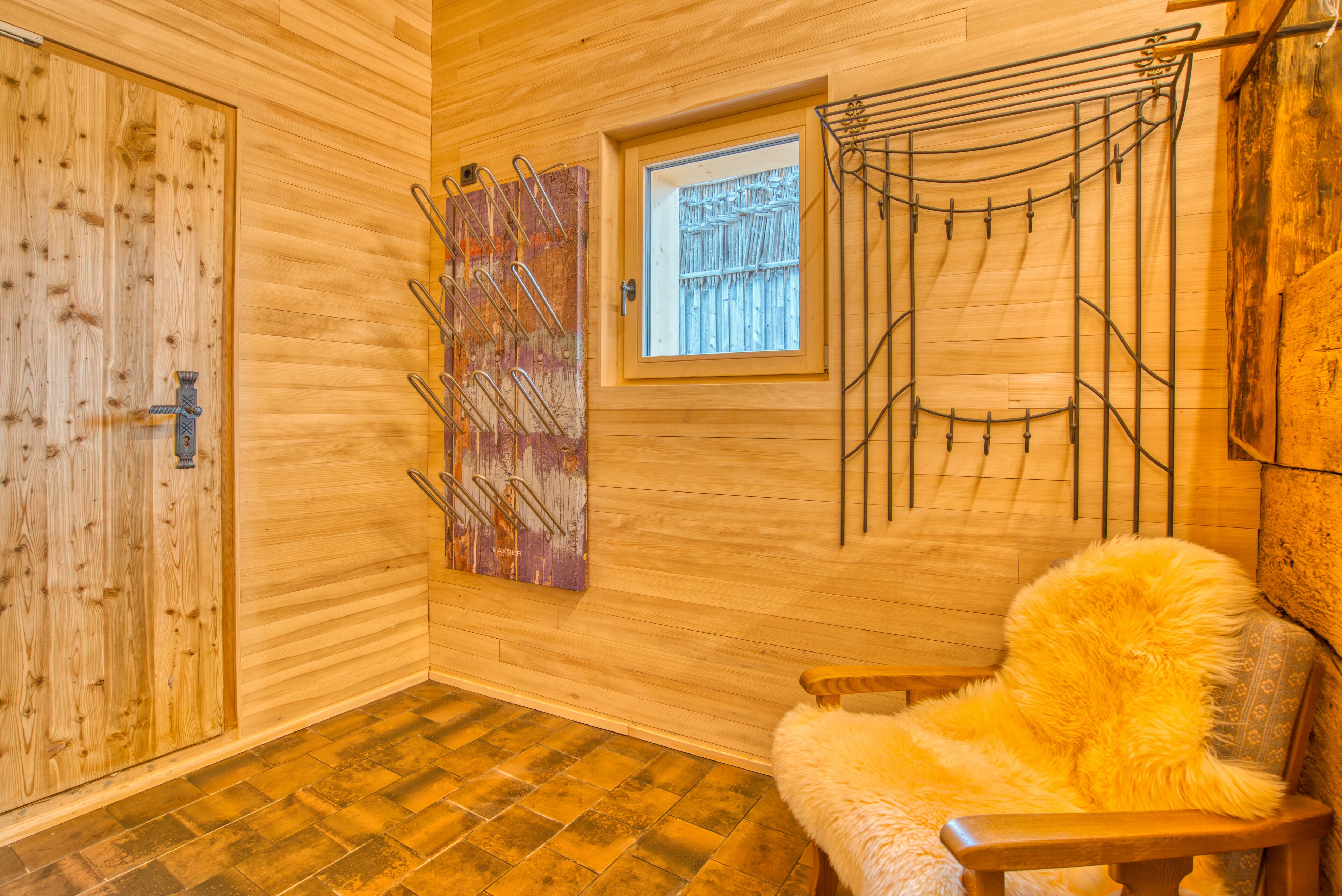 Quarto de madeira com sauna, porta de madeira, janela e uma cadeira.
