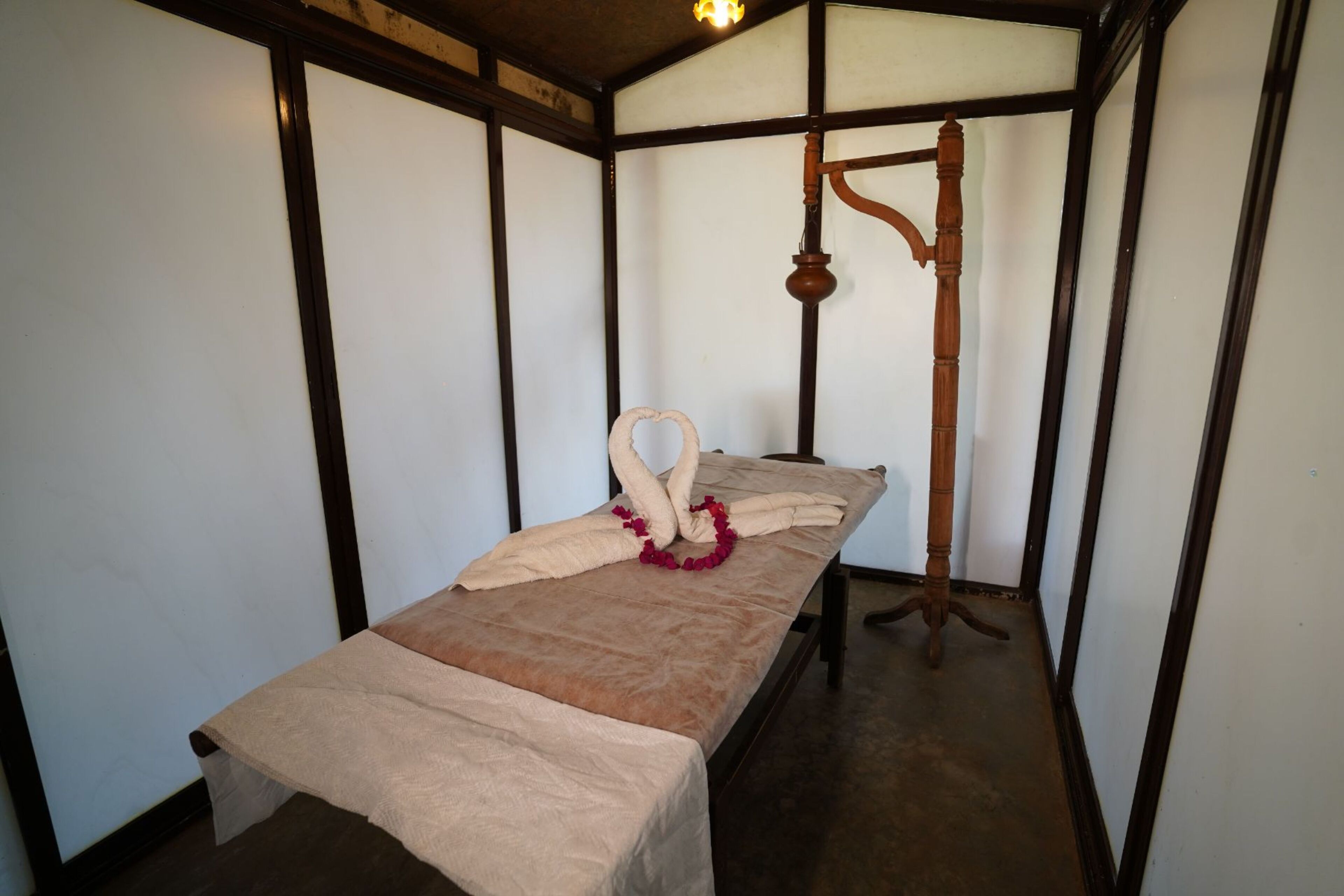 Quarto com cama, cabeceira de madeira e luminária no teto.