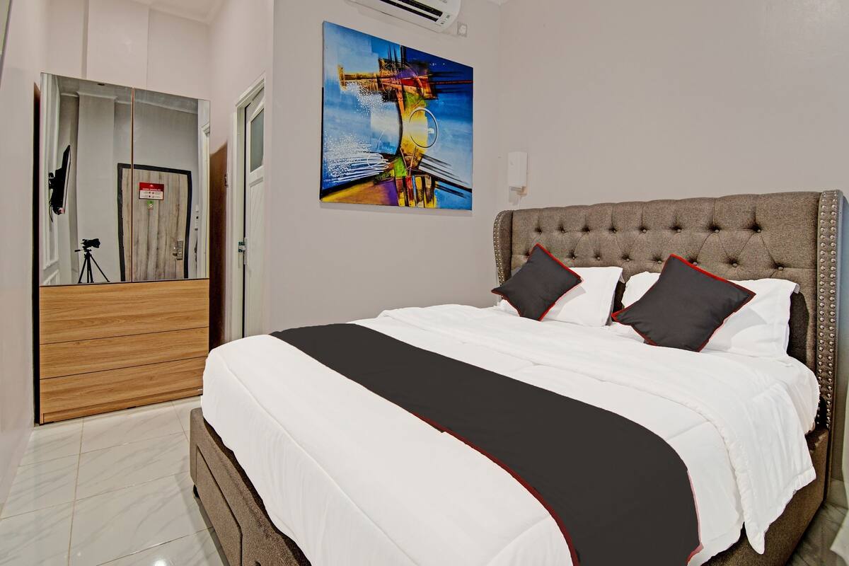 Quarto com cama grande, espelho e um quadro na parede.