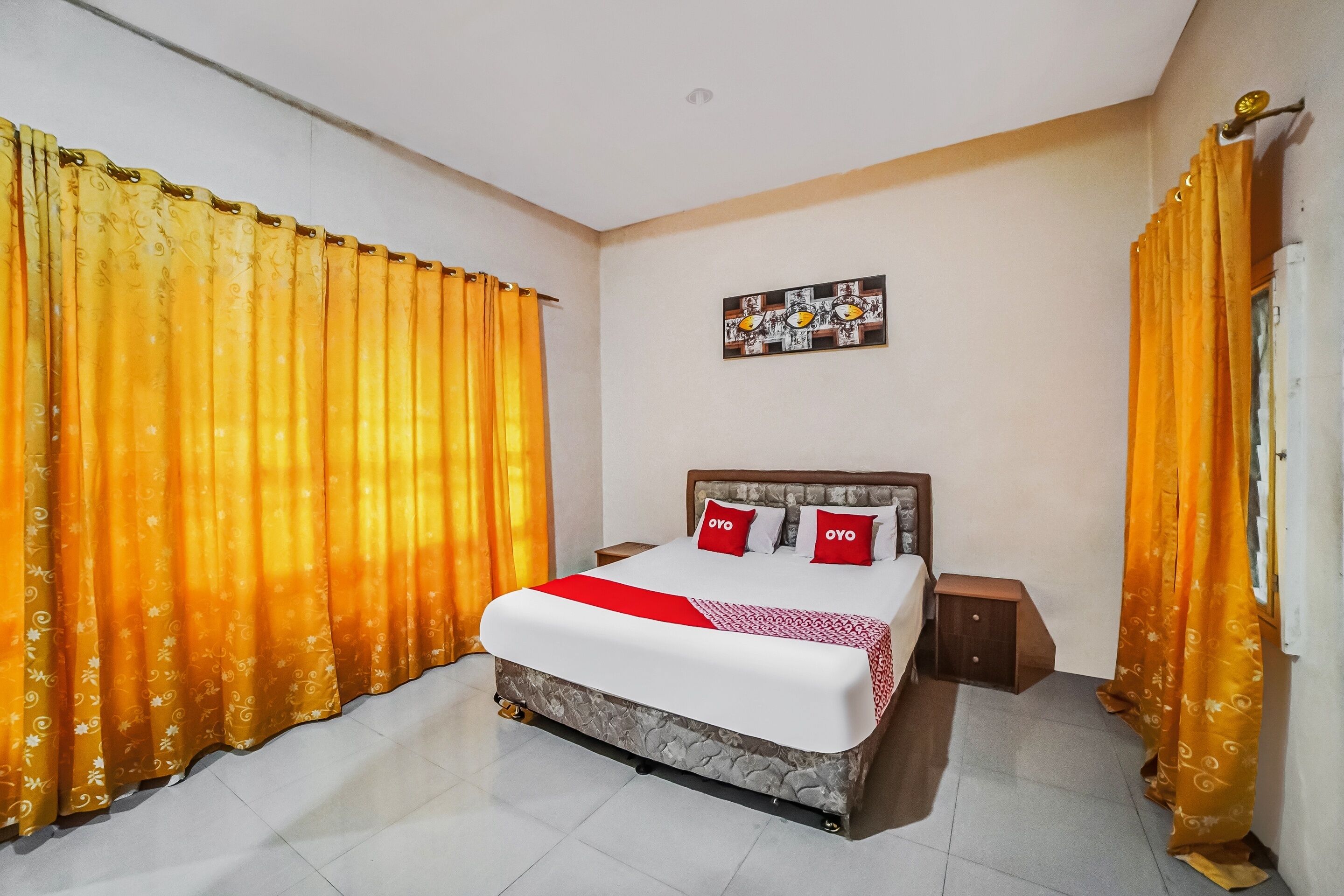 Quarto de hotel com cama, cortinas, relógio de parede e pequena mesa de cabeceira.