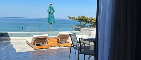 Quarto com uma grande porta de vidro deslizante que dá para uma varanda com vista para o mar.