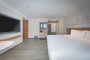 Quarto de hotel moderno com uma cama grande, televisão, guarda-roupa e banheiro.